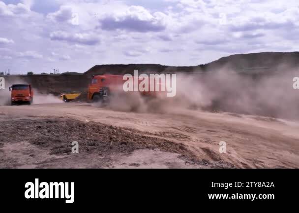 Big, red excavators moving at a sand quarry with flying dust. Scene ...