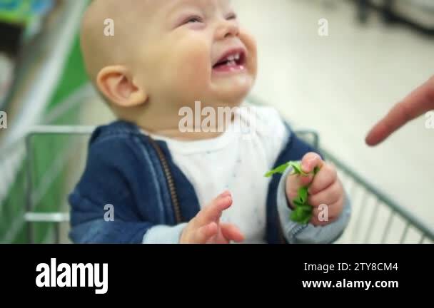 Cute baby laughs full mouth sitting in a supermarket trolley. His first ...