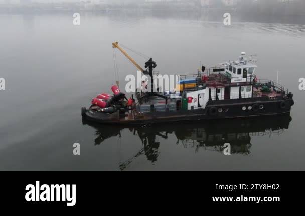 A barge loaded with scrap metal and waste floating on a water surface ...