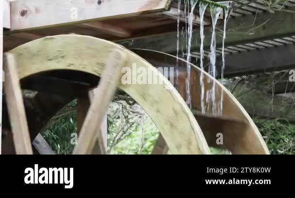 Water wheel of an old-fashioned mill rotating under the pressure of the ...