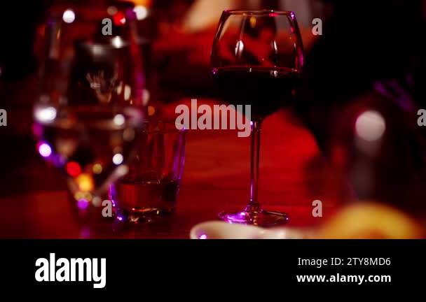 A classic bartender pours sparkling wine from a tall glass into a cocktail glass in the interior ...