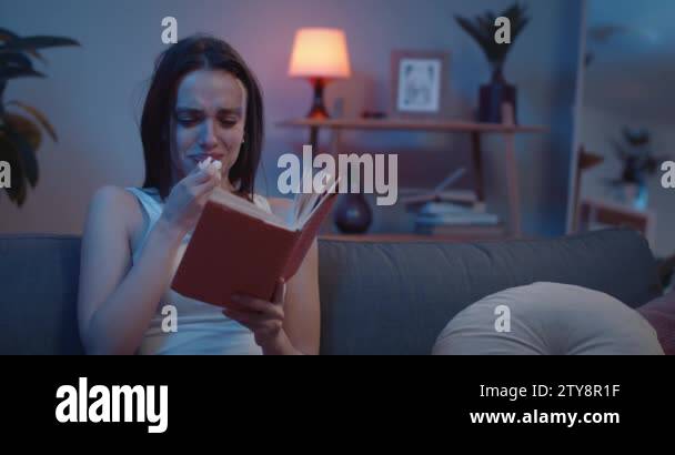 Front view of young upset girl with tears on her face reading book ...