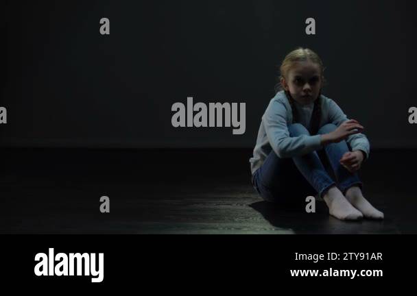 Scared little girl sitting alone in dark room, loneliness and bullying ...