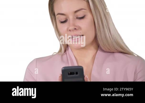 Trendy smiling blond woman using her mobile phone smiling as she types ...