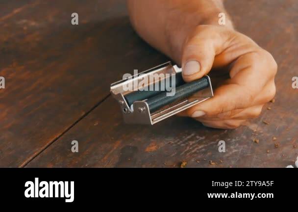 Mens hands make handmade cigarette or roll-ups with roll-up machine ...