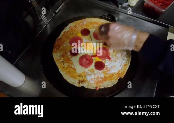 Cook preparing a crepe with cheese, Turkish sauge (sucuk) and egg Stock ...