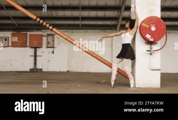 Side view of a mixed race female ballet dancer practicing in an empty ...