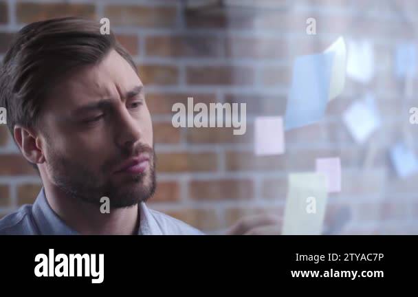 Concentrated businessman with pencil blinking and writing on sticky ...