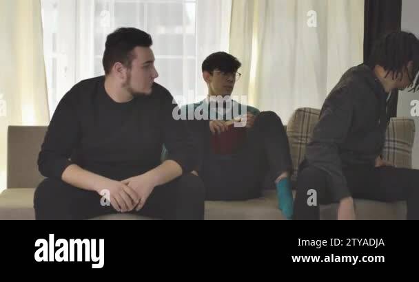 Hippie boy and plump guy talking and watching TV as their nerd ...