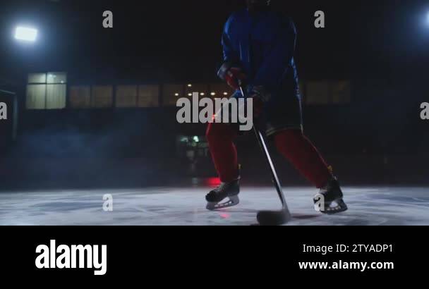 Male hockey player with a puck on the ice arena shows dribbling moving ...