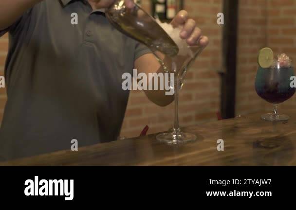 Barman putting crushed ice in glass for making cocktail at bar counter of restaurant. Bartender ...