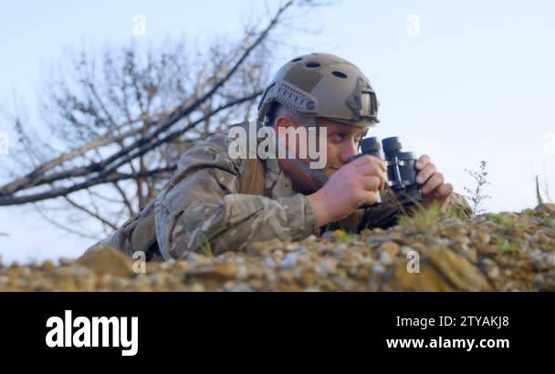 Side view of military soldier looking through binoculars during ...