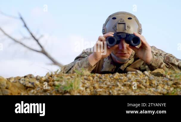 Front view of military soldier looking through binoculars during ...