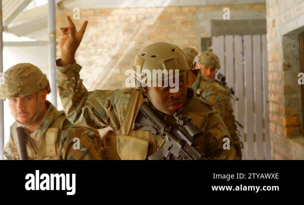 Front view of mixed-race military soldiers walking with rifles during ...