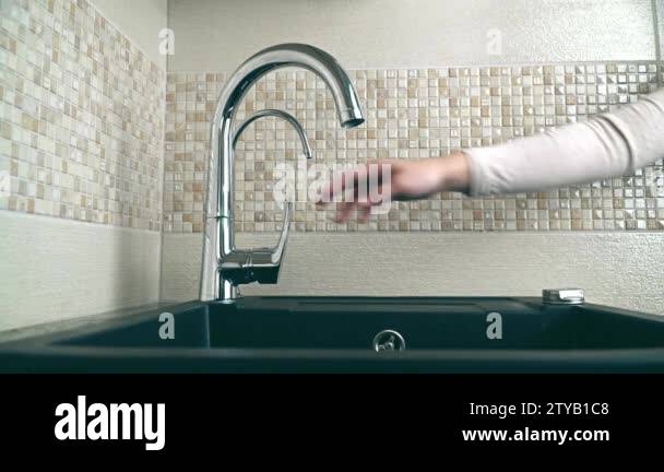 Close up female hands opening water tap in kitchen. Tap water from a ...