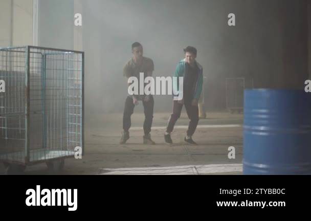 Two friends dancing in the dark and dusty room of abandoned building ...