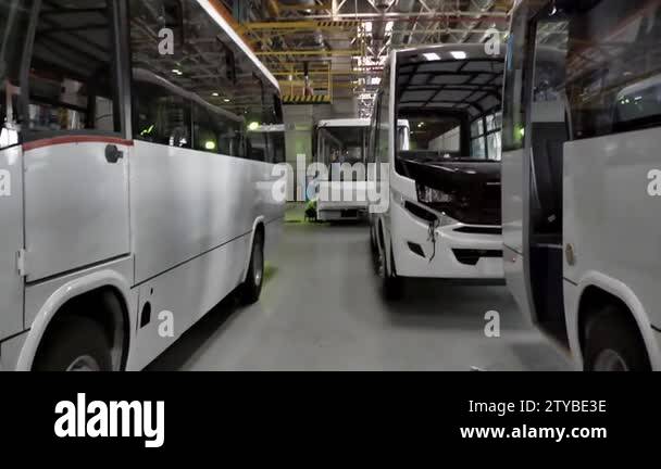 Close up for bus production line at a factory. Scene. New, modern, white buses standing indoors ...