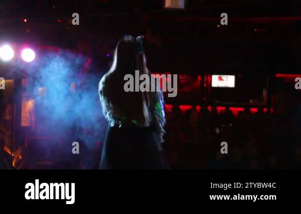 Girl who sings and dances on stage, Back view of singer. Light and ...