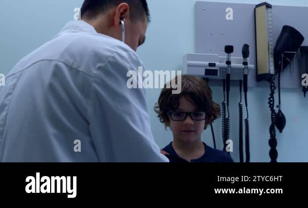 Rear view of young asian male doctor examining caucasian boy patient ...