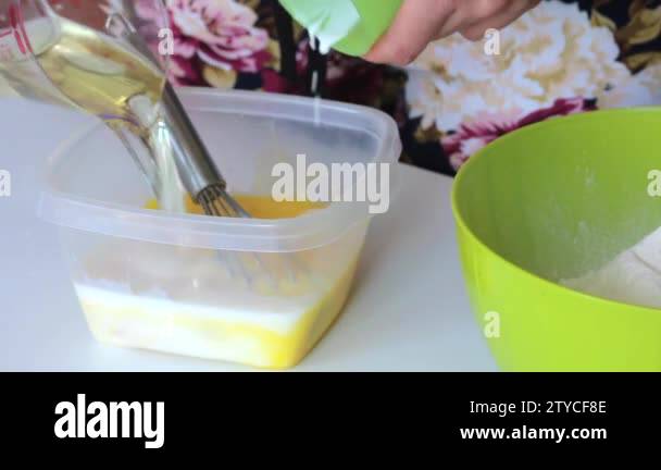 A woman is mixing in a container the ingredients for making dough. Cake ...