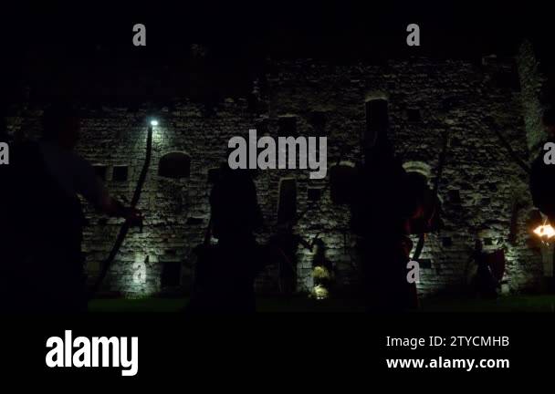Archers launch fire arrows in the medieval castle at night during the ...