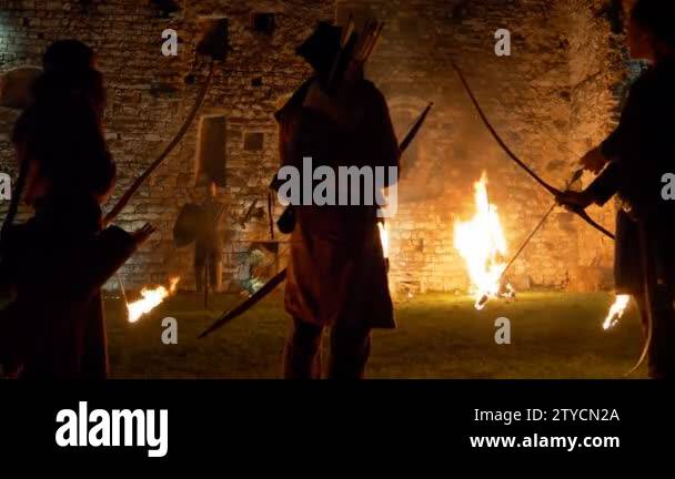 Archers launch fire arrows in the medieval castle at night during the ...