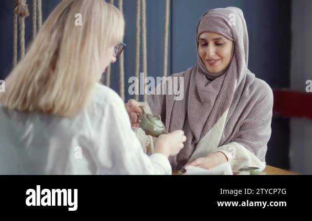 Women of muslim and western traditions are drinking tea together in ...