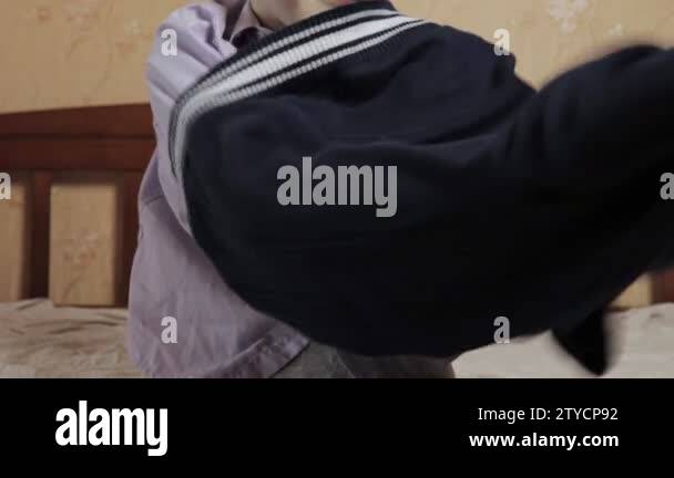 A schoolboy taking off sweater and unbutton his shirt, changing clothes ...