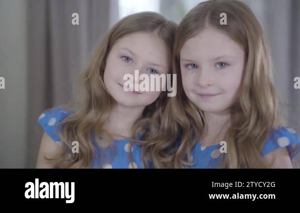 Camera moving away from faces of charming little twin sisters smiling ...