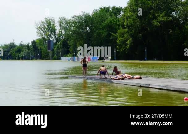 People in swimsuit sunbathing and having fun on a river wooden pier, 4k ...