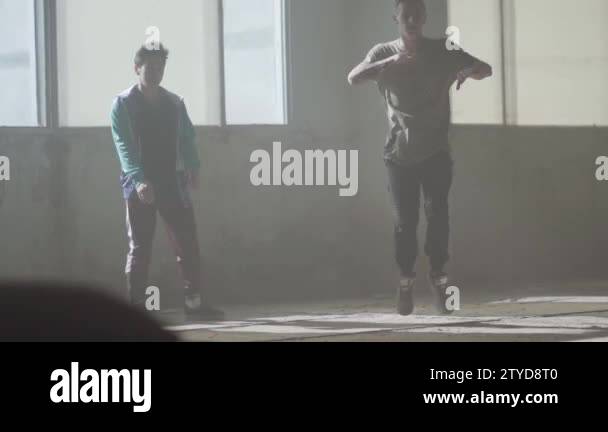 Two boys dancing in front of the large window in abandoned building ...