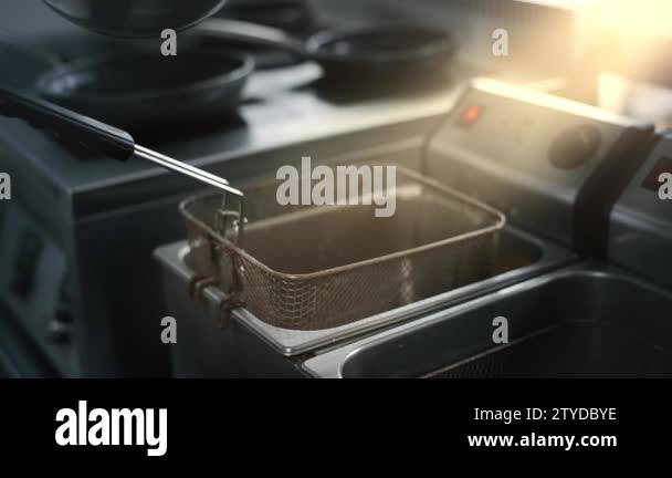 The cook fills the fryer with raw potato for making fries in slow ...