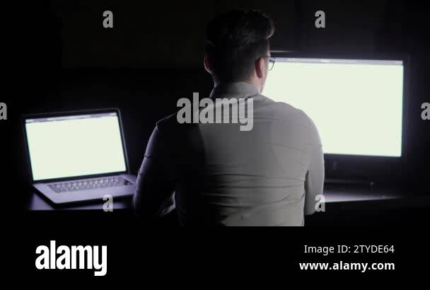 Programmer man is working in the office overtime late at night sitting ...