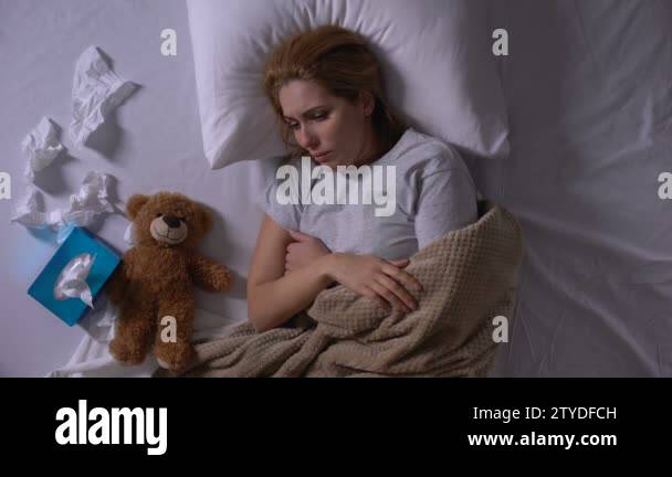 Depressed woman in bed crying, hugging teddy-bear, suffering from ...