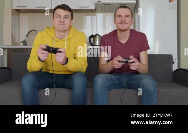 Two men are playing video game against each other. Young guys are ...