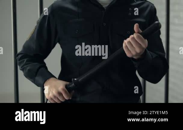 Prison security guard standing near cell with truncheon, strict regime ...