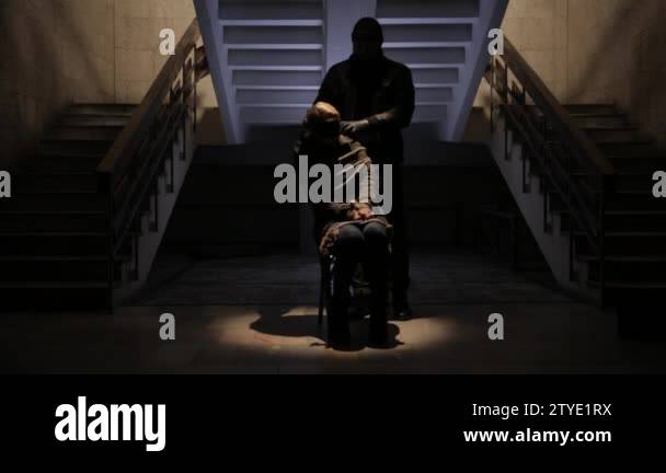 Kidnapped tied woman on the chair. The criminal makes an injection into ...