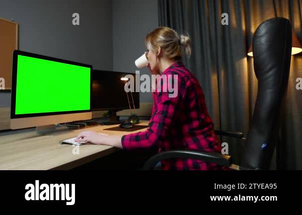 Woman works on her computer, works in office. Monitor green screen ...
