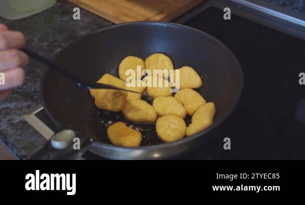 fried chicken nuggets meat are being cooked deep fried in a hot boiling ...