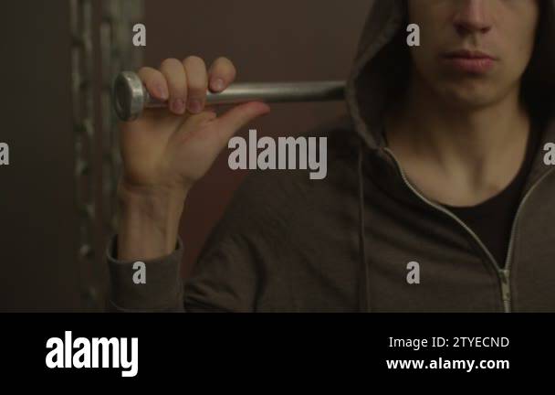 Aggressive grim looking street hooligan in hoodie holding baseball bat ...
