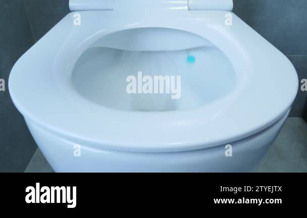 White toilet, front view. Close up view of water flushing down into the ...