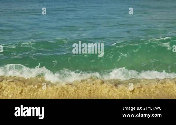 A slow motion footage of wave mixing with sand as it rushes to shore ...