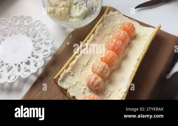 Cooking biscuit roll stuffed with ricotta and mandarin. Woman puts ...