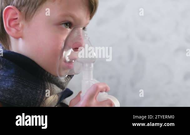 Sick boy inhaling through inhaler mask, face close-up side view. Use ...