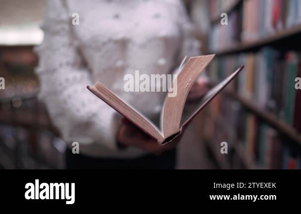 Unrecognizable woman beautifully turns over the pages of old paper book ...