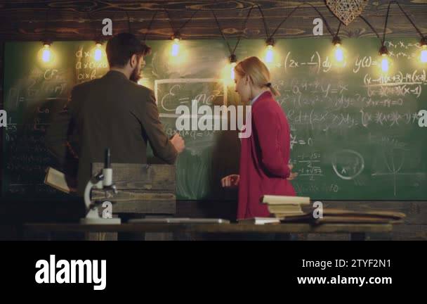 Bearded professor and girl student decide formulas that are written on ...