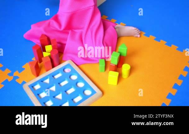 Little Asian cute girl playing cubes, sitting on a color floor. The ...