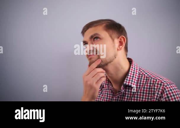 Thinking young man in a plaid shirt raises his finger up. A brilliant ...