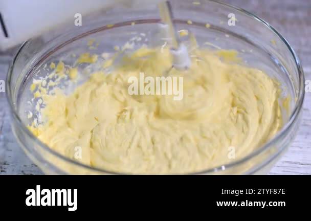 Mixing white cream in bowl with mixer. Electric mixer whipping cream in ...