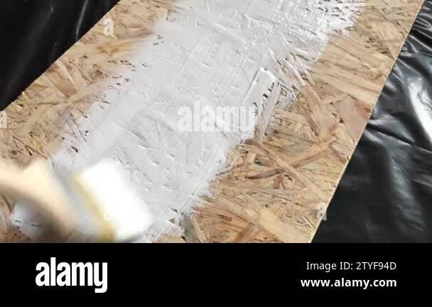 The process of painting a wooden shelf from OSB panel in white on a ...